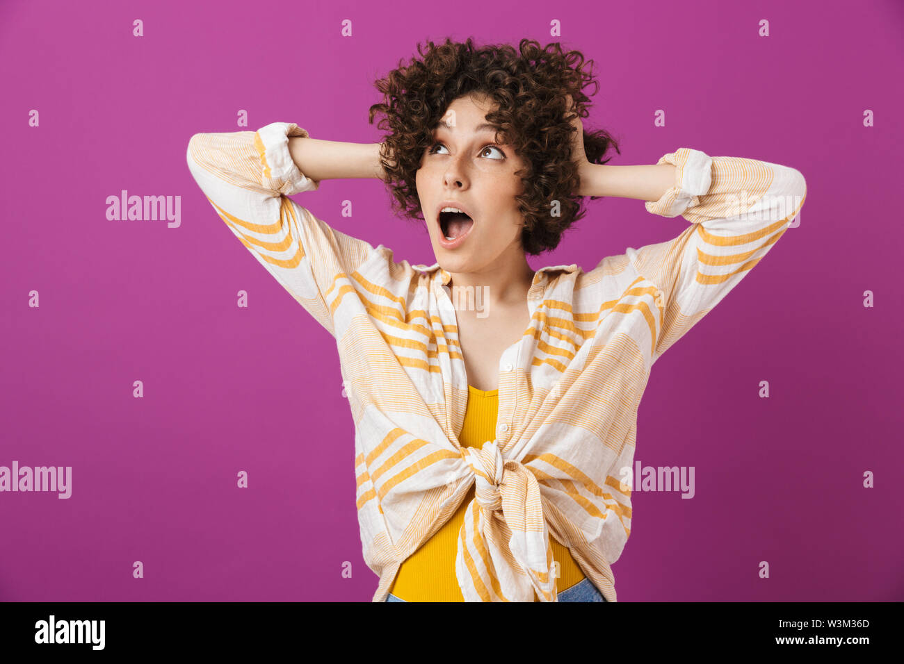 Portrait of an attractive shocked young woman with curly brunette hair ...