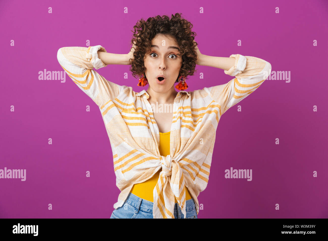 Portrait of an attractive shocked young woman with curly brunette hair ...