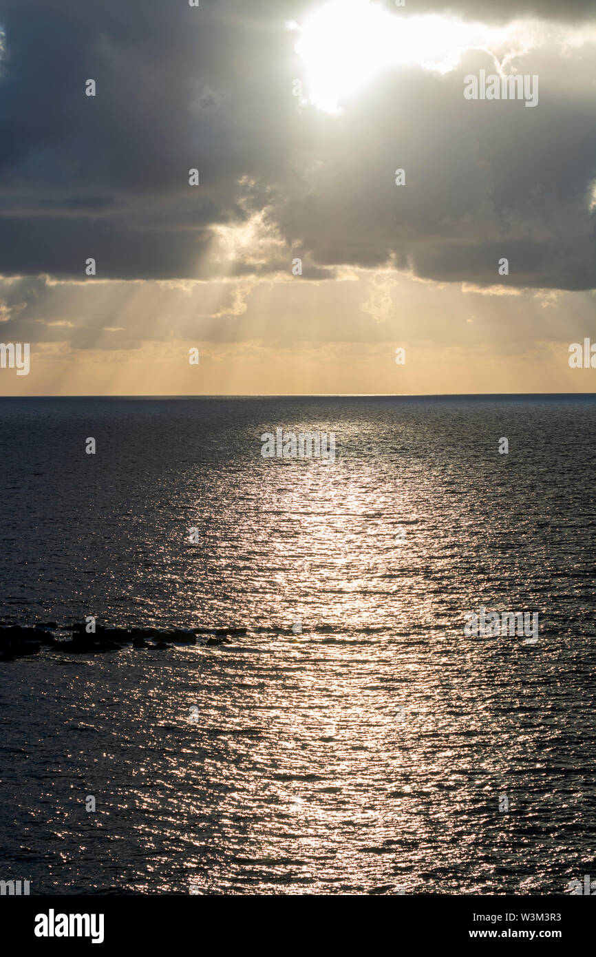 Dramatic sunset over sea water with gray clouds and sun lights, nature ...