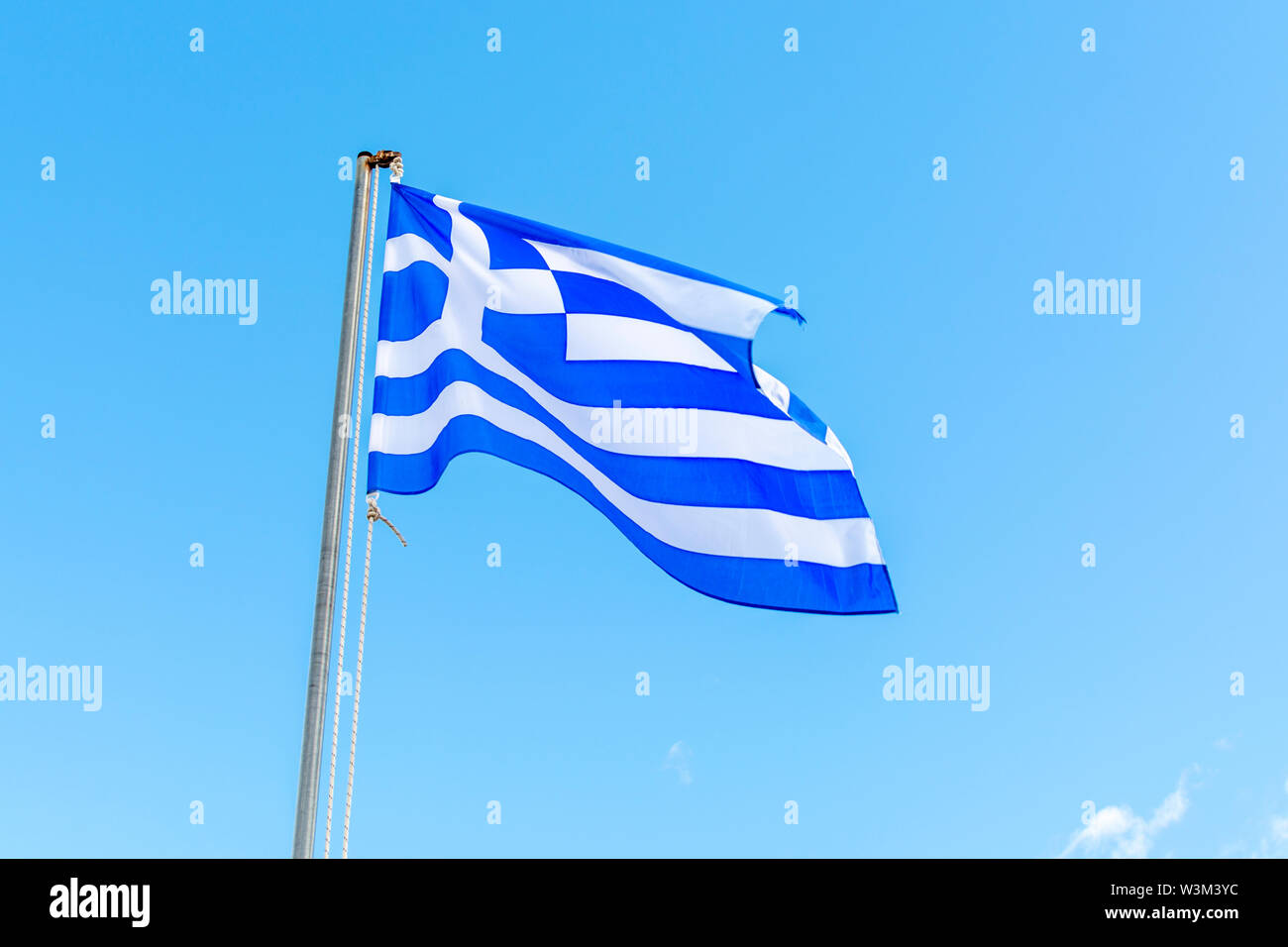 National symbol of Greece, blue-white greek flag on flagpole, sea water ...