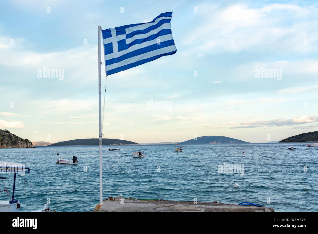 National symbol of Greece, blue-white greek flag on flagpole, sea water ...