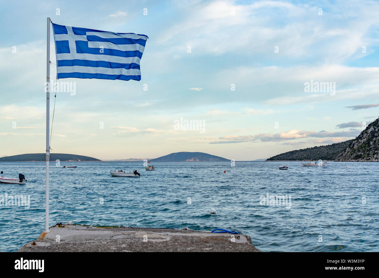 National symbol of Greece, blue-white greek flag on flagpole, sea water ...