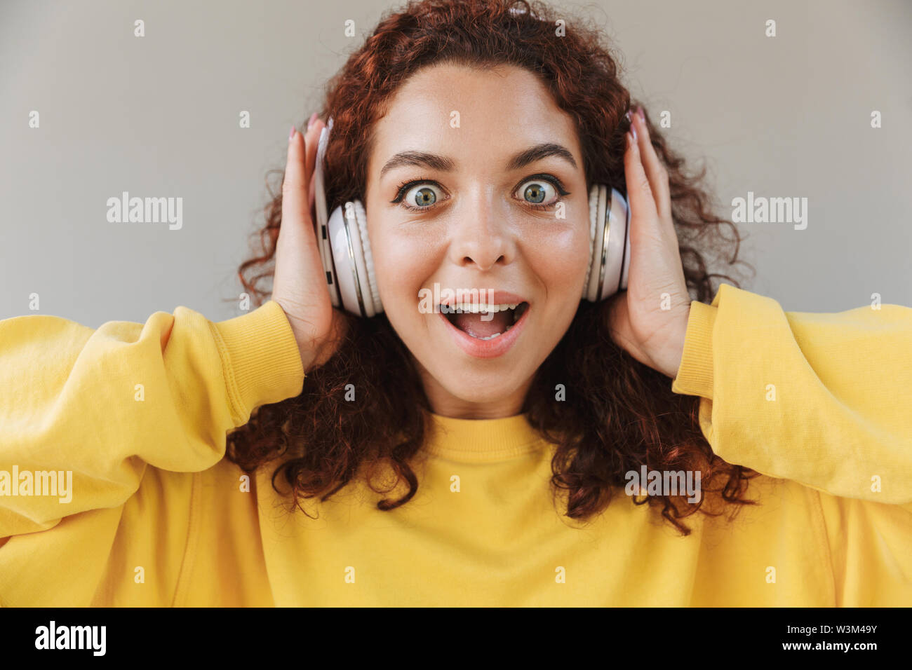 Portrait Of A Shocked Excited Beautiful Curly Girl Isolated Over Gray