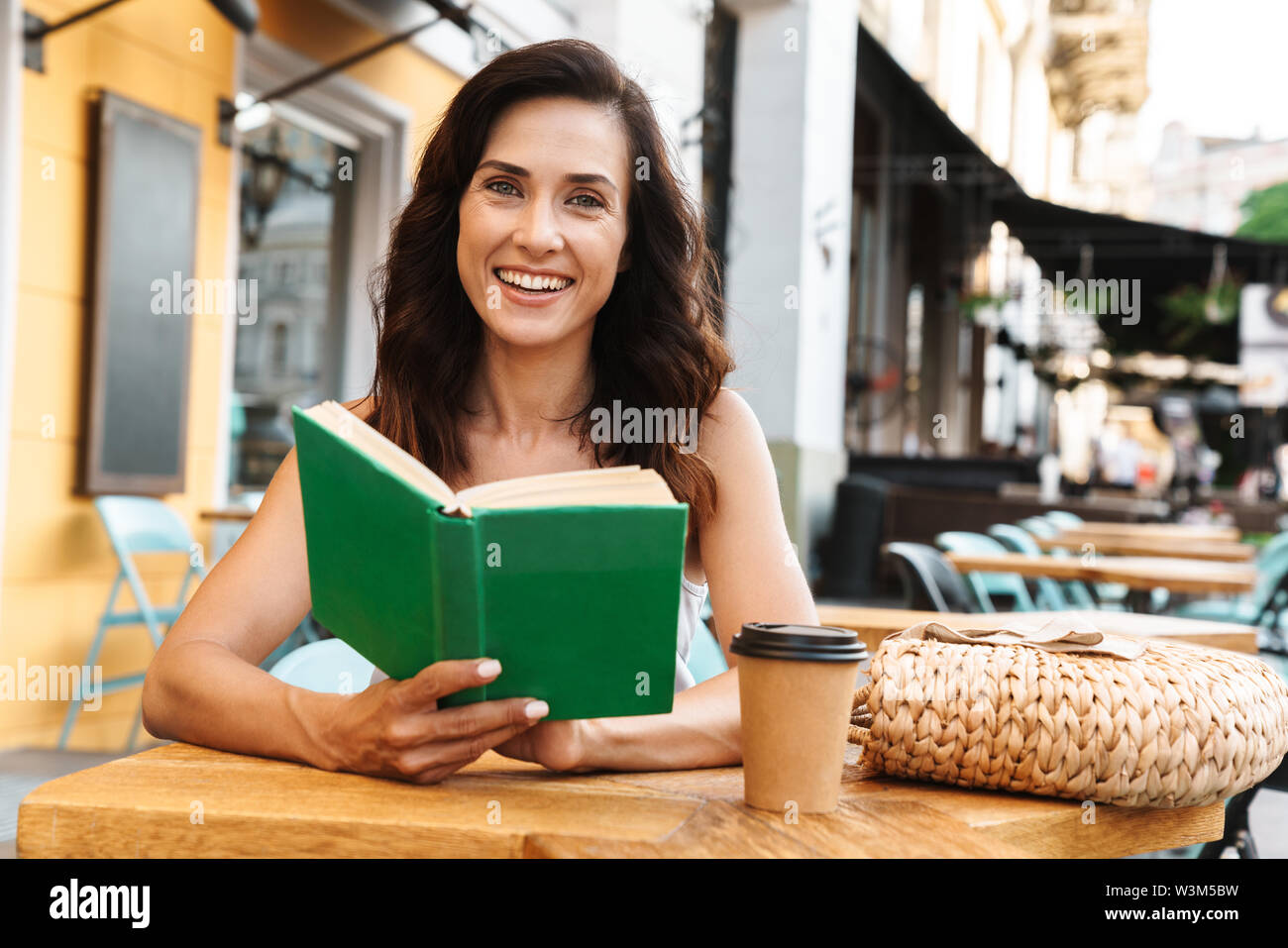 Portrait of positive nice woman with straw bag drinking coffee from ...