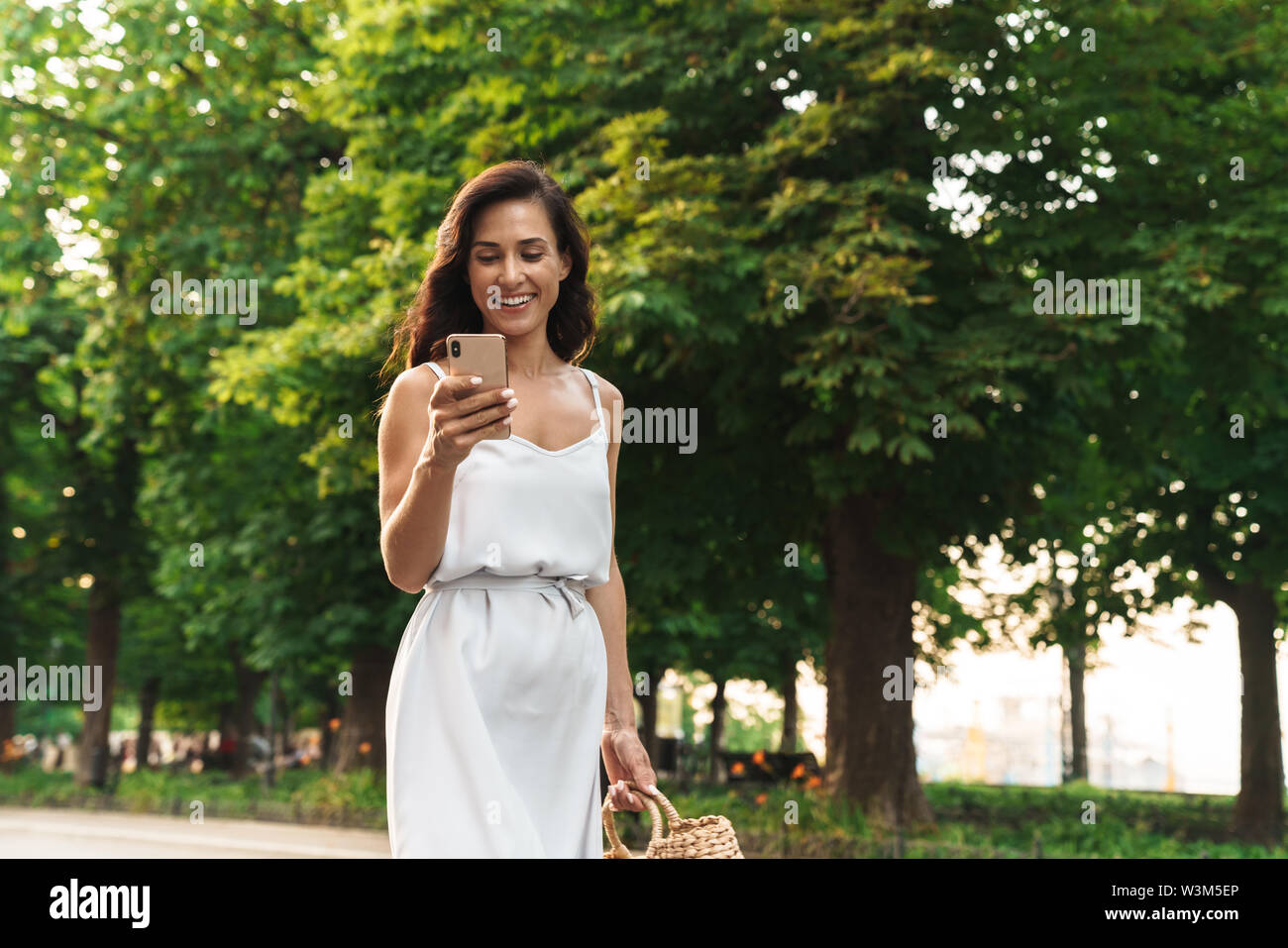 Portrait of beautiful woman in summer dress smiling and holding ...