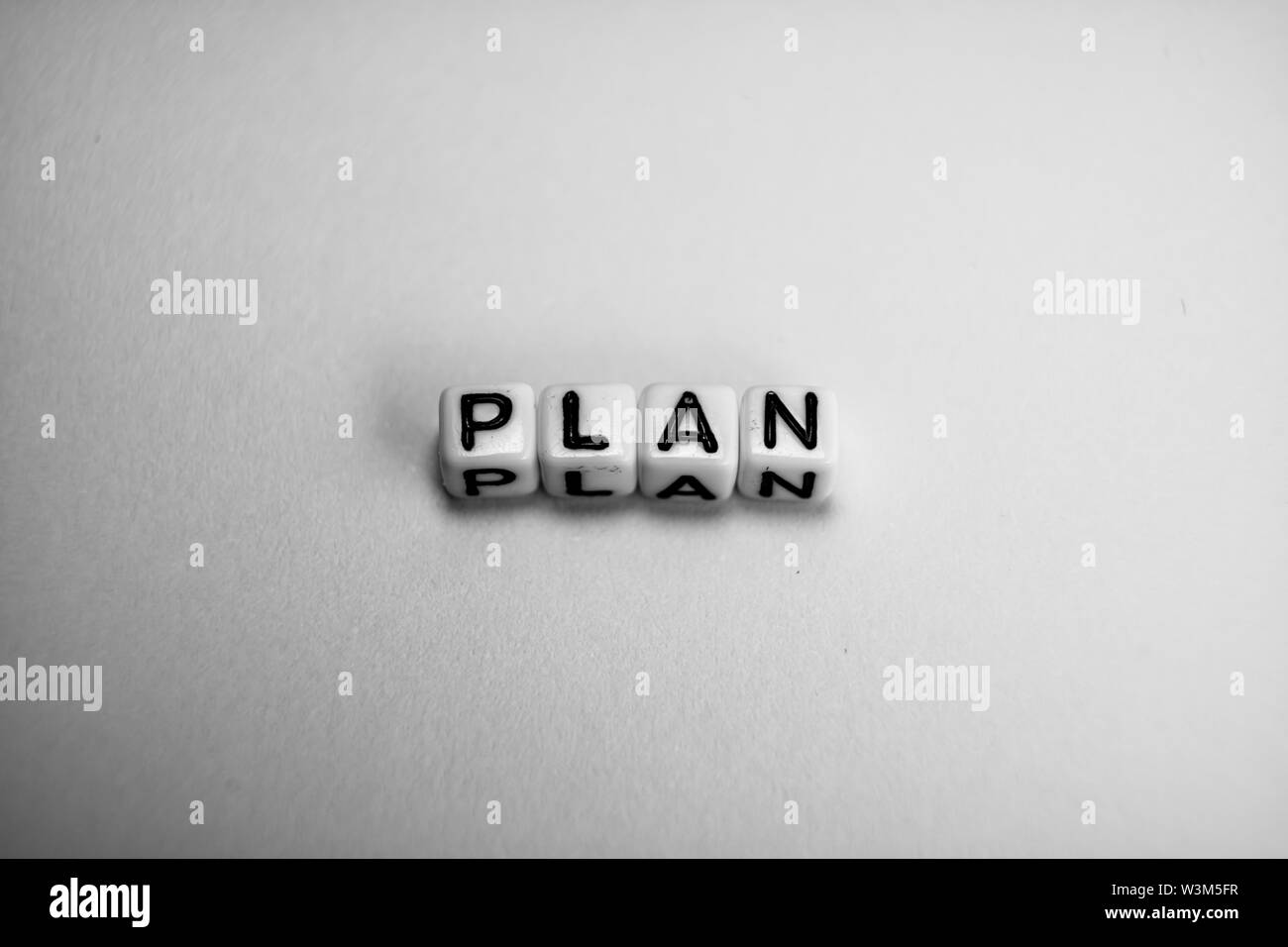 White cubes with word PLAN on white paper background and dark shadows ...