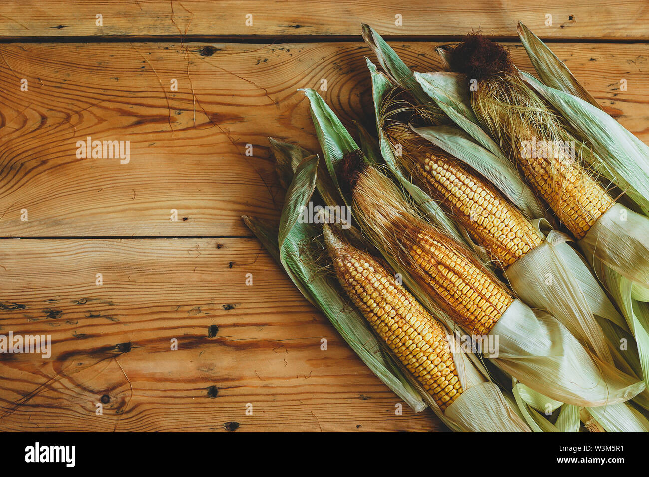 Fresh raw corn cobs on wooden background. Raw corn with skin. Sweet ...