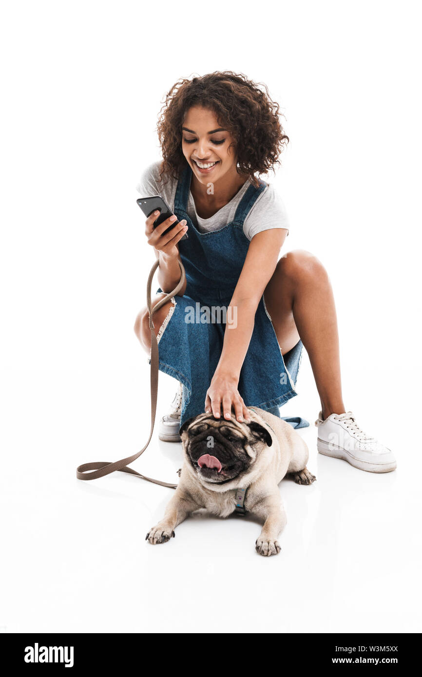 Image of happy african american woman using cellphone and squatting ...