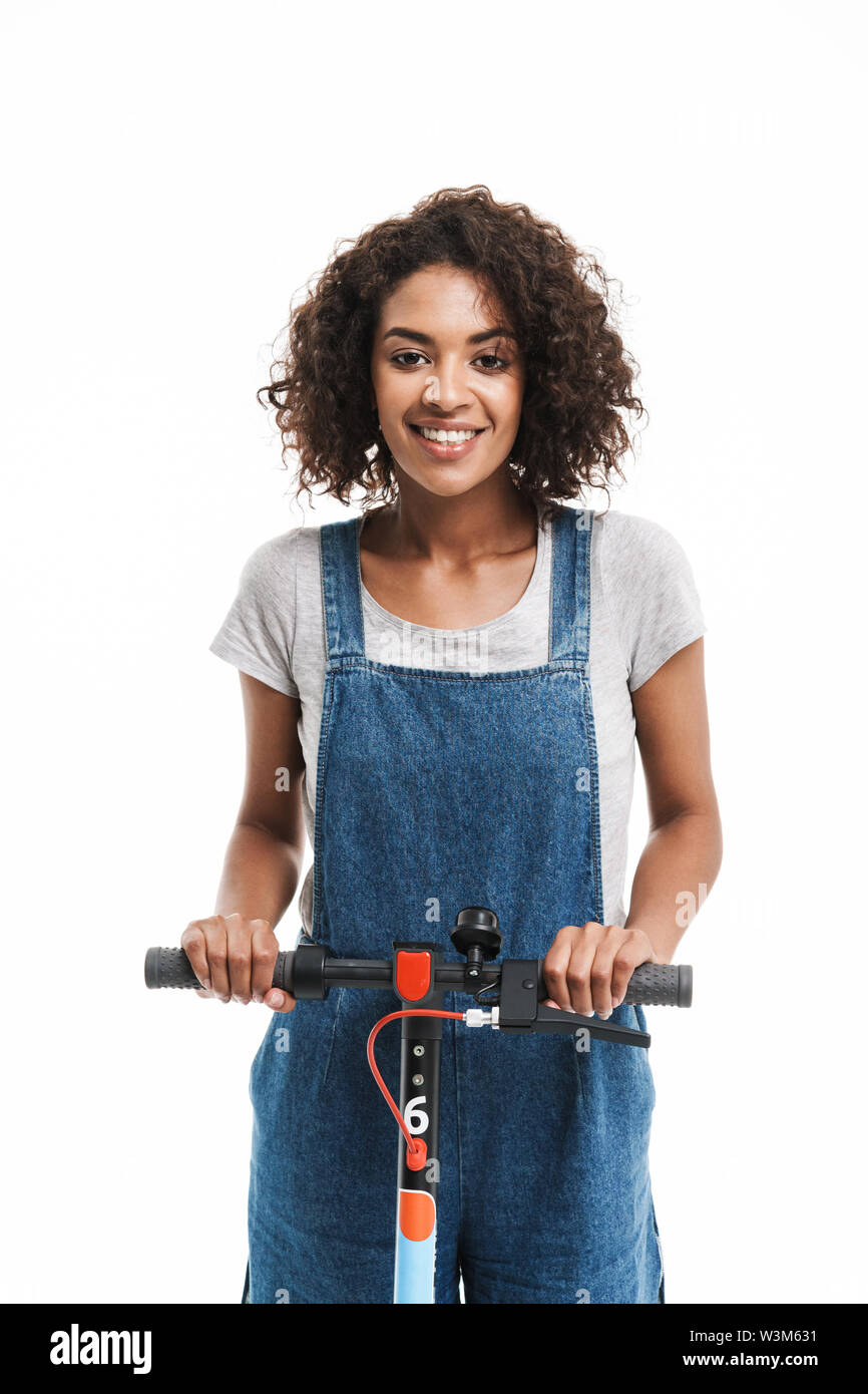 Image of happy african american woman dressed in denim overalls smiling ...