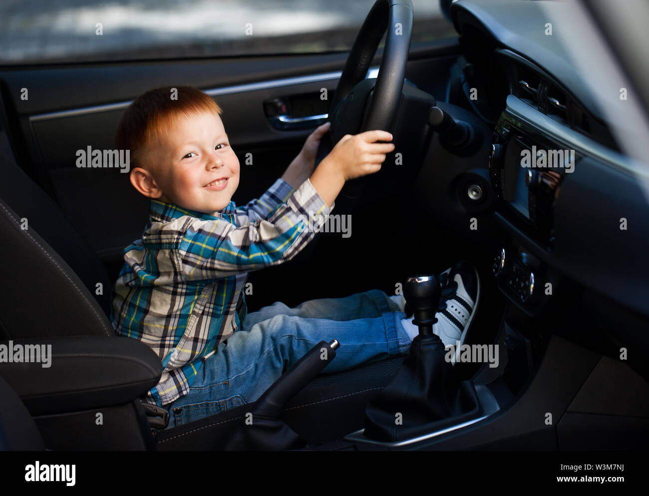 Cute little boy smiling and driving fathers car Stock Photo - Alamy