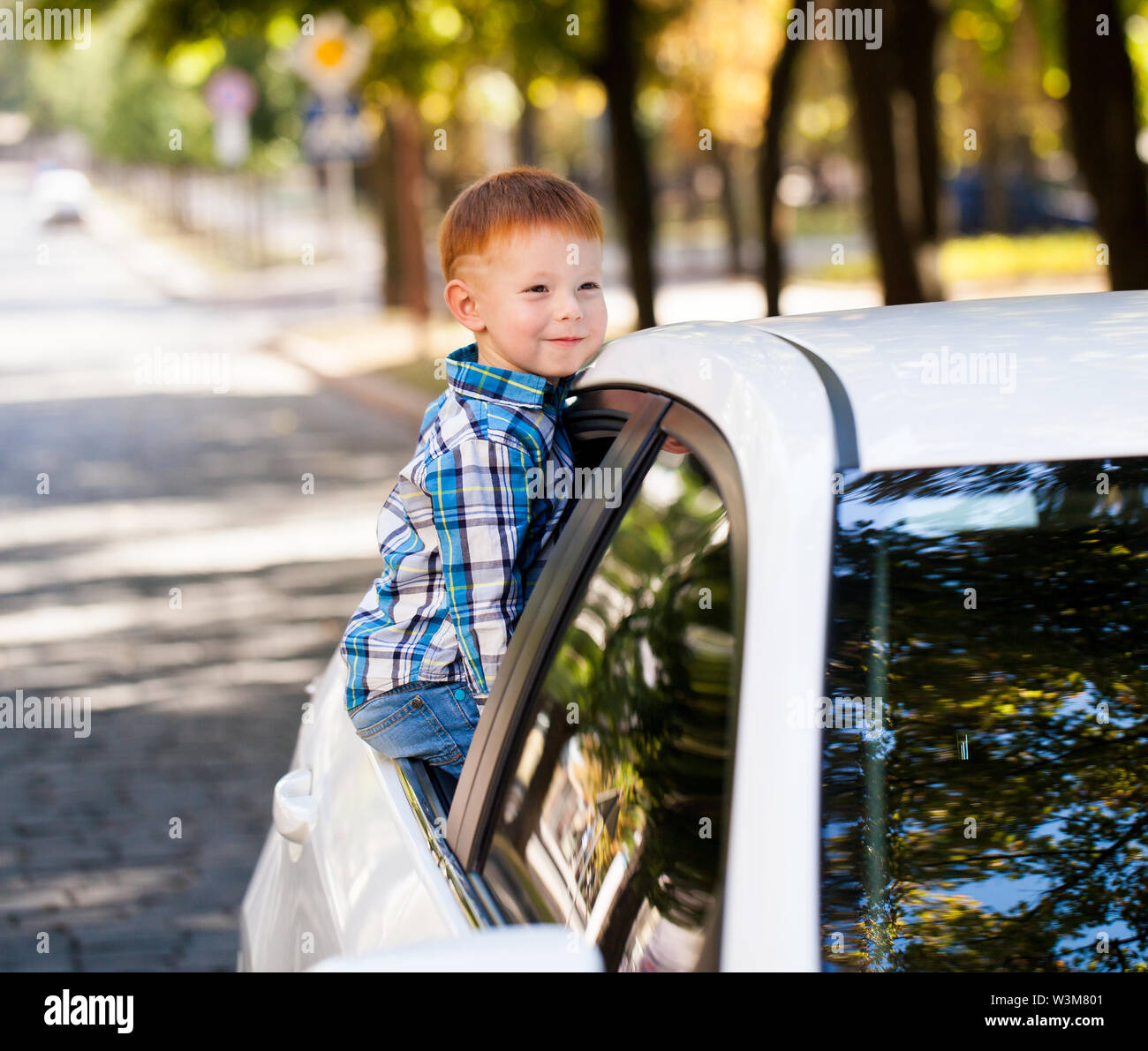 Adorable baby boy in the car. Laughing boy looks out of the car window ...