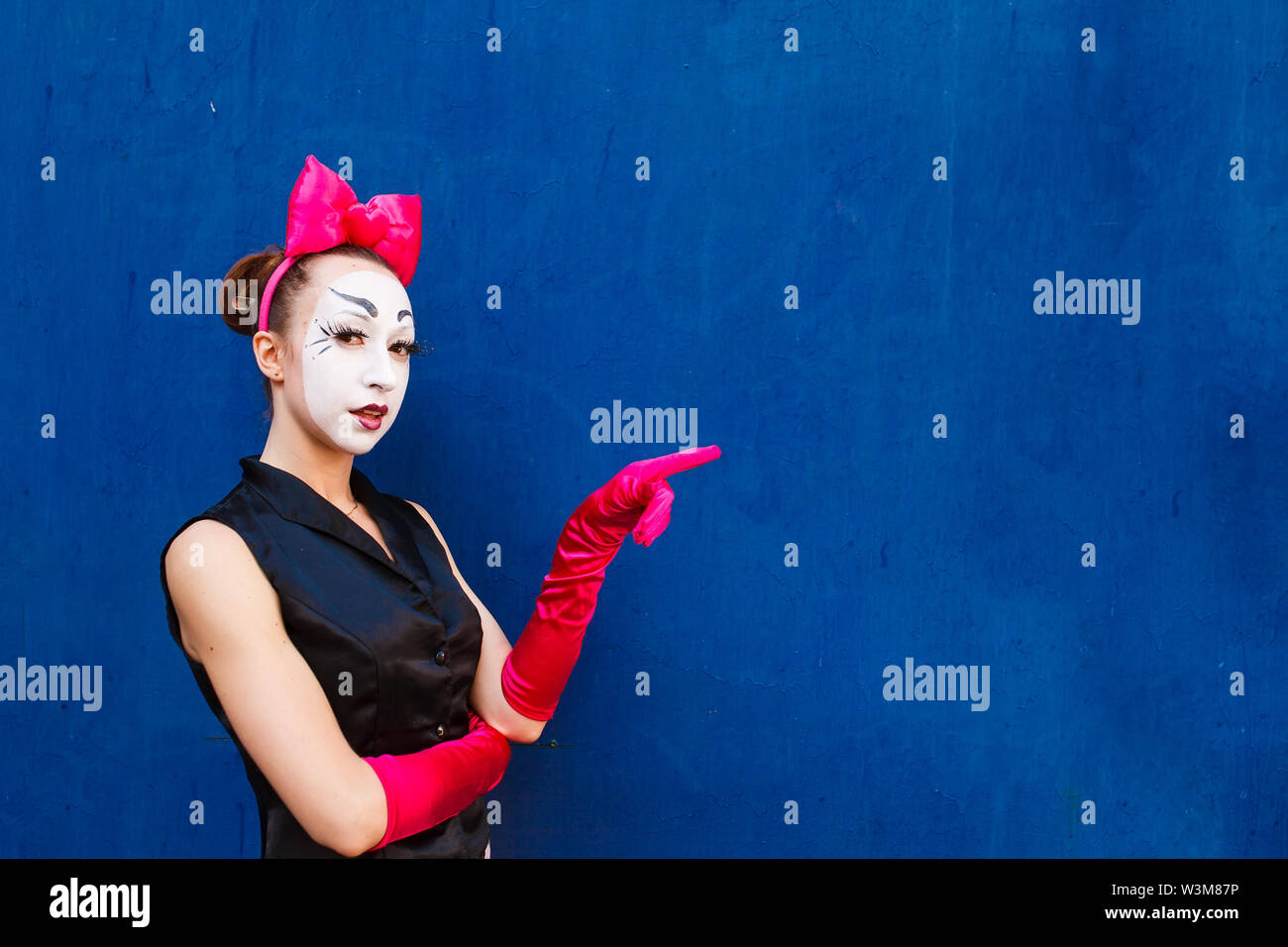 Mime points a finger at the center against a background of a blue wall ...