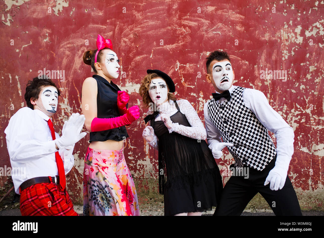Four mimes standing in awe at the background of a red wall Stock Photo ...