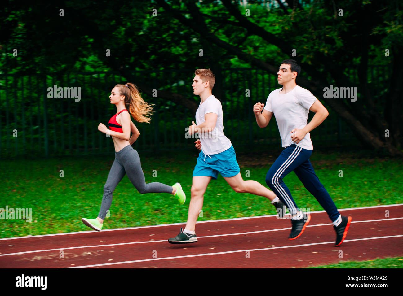 Running young people at a stadium track Stock Photo - Alamy
