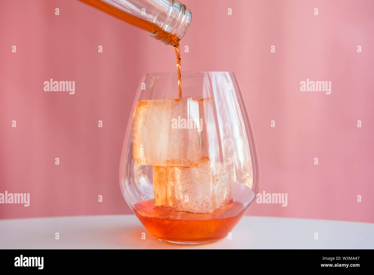 Liquor being poured into glass with ice cubes Stock Photo - Alamy