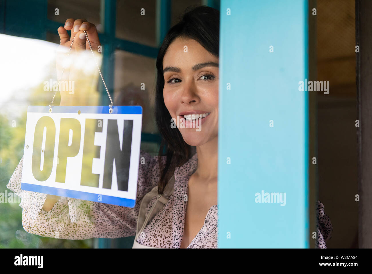 Woman turning open sign in shop window Stock Photo - Alamy