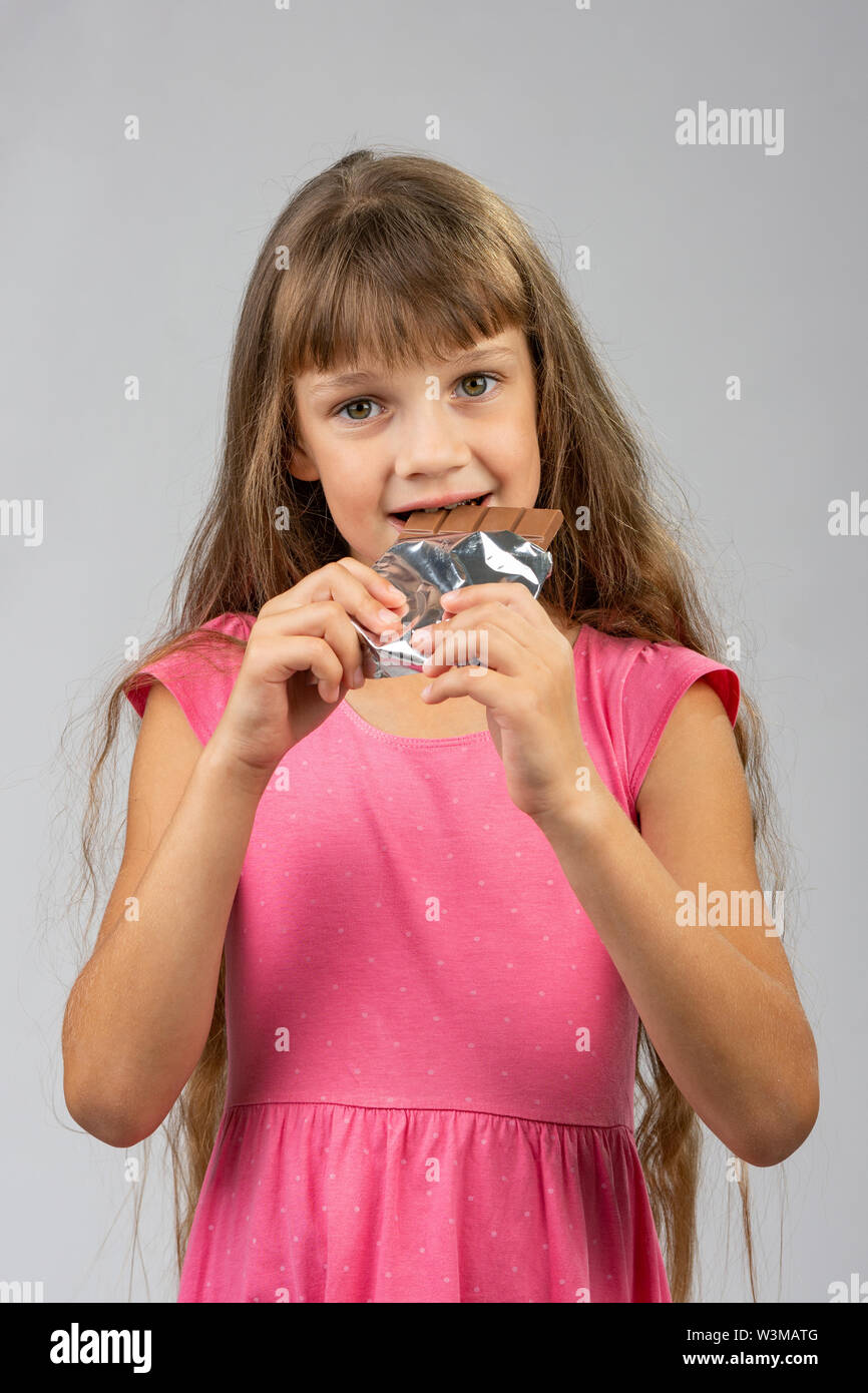 Eight-year-old girl eats chocolate bar Stock Photo - Alamy