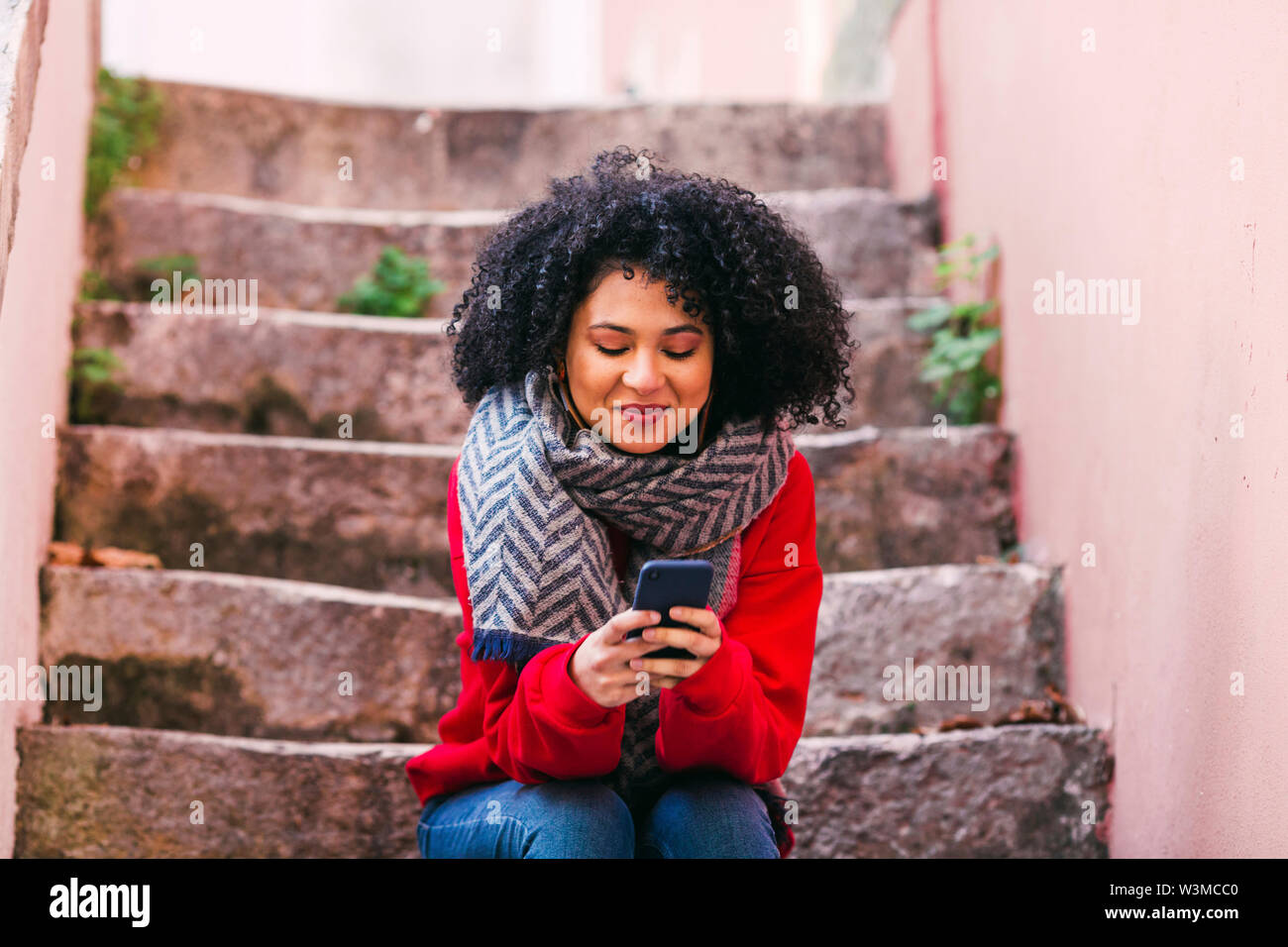 Young woman with smart phone sitting on steps Stock Photo - Alamy