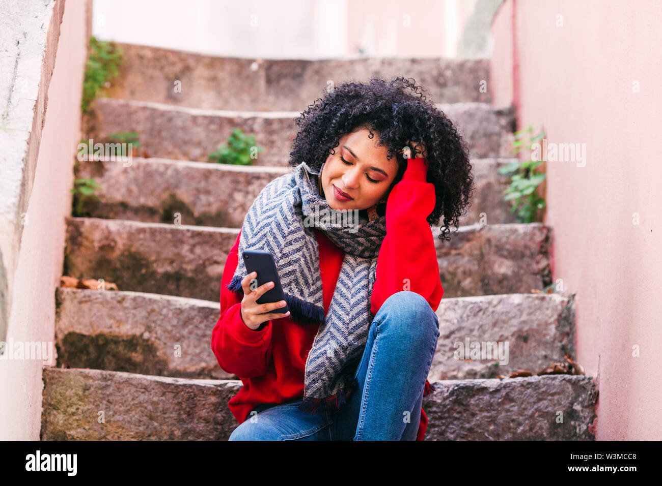 Young woman with smart phone sitting on steps Stock Photo - Alamy