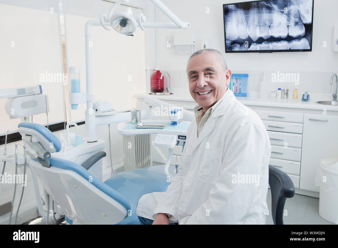 Dentist smiling in dentist's surgery Stock Photo - Alamy