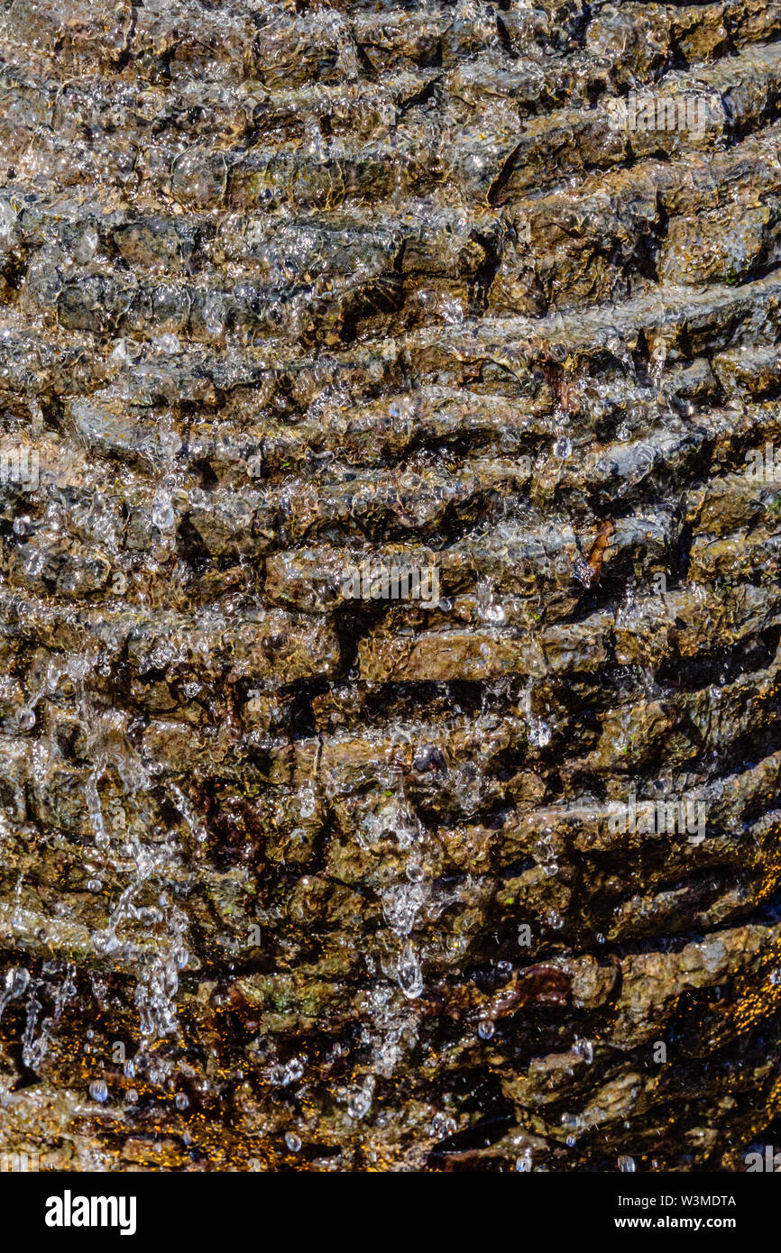 Stone masonry with running water flowing down with water foam ...