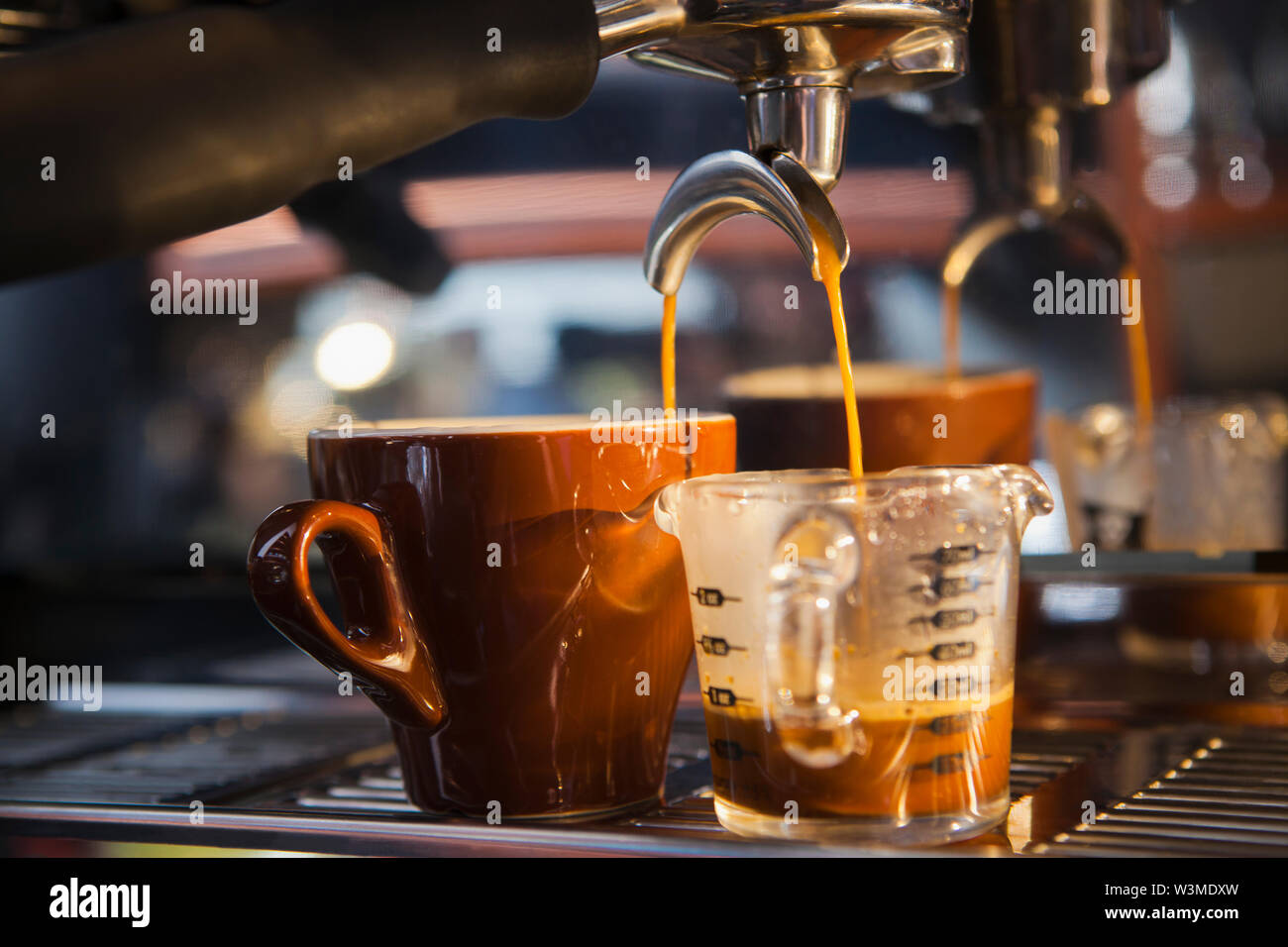 Coffee pouring from portafilter into coffee cup and beaker Stock Photo ...
