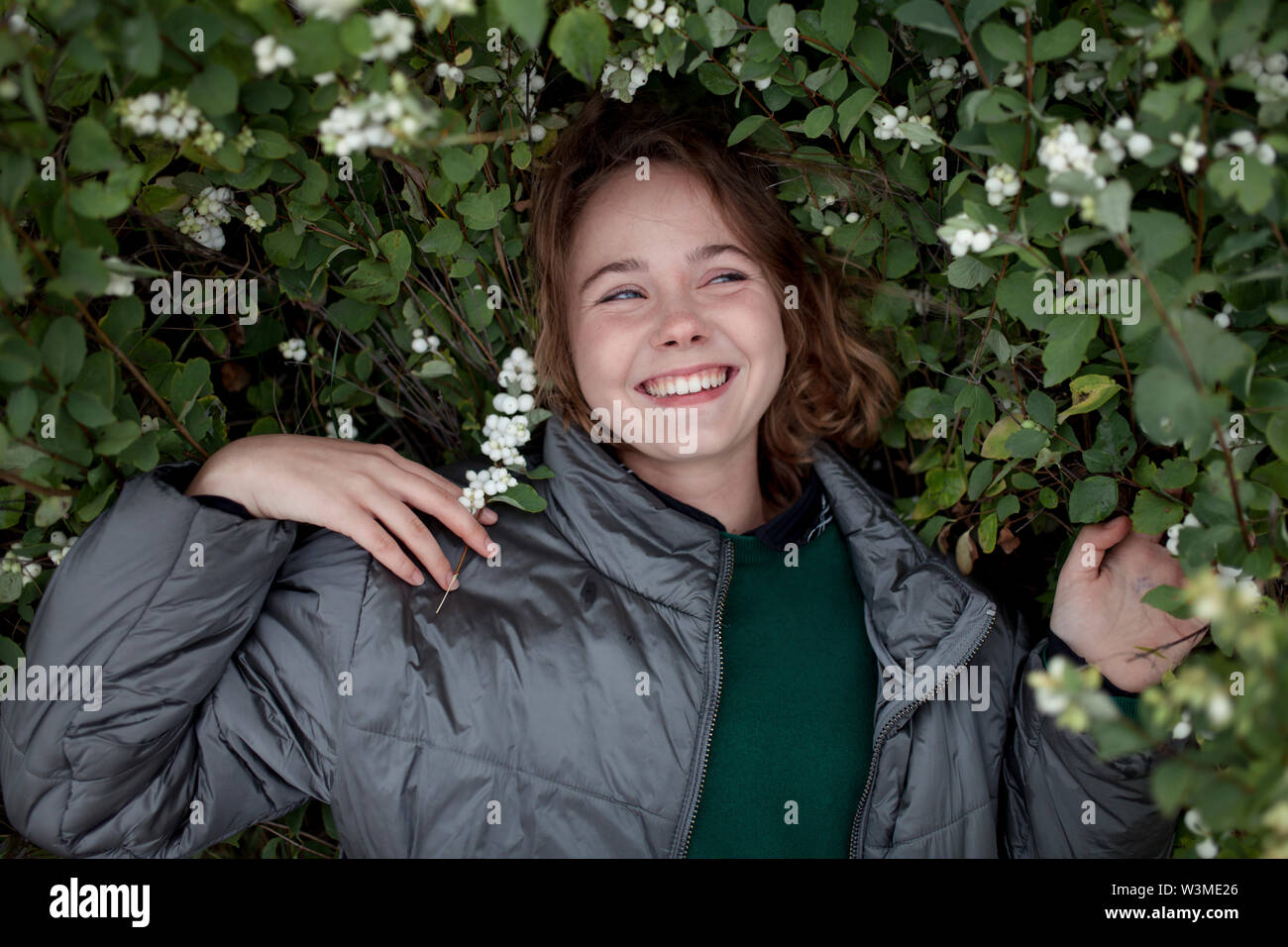 Teenage girl in bush with flowers Stock Photo - Alamy