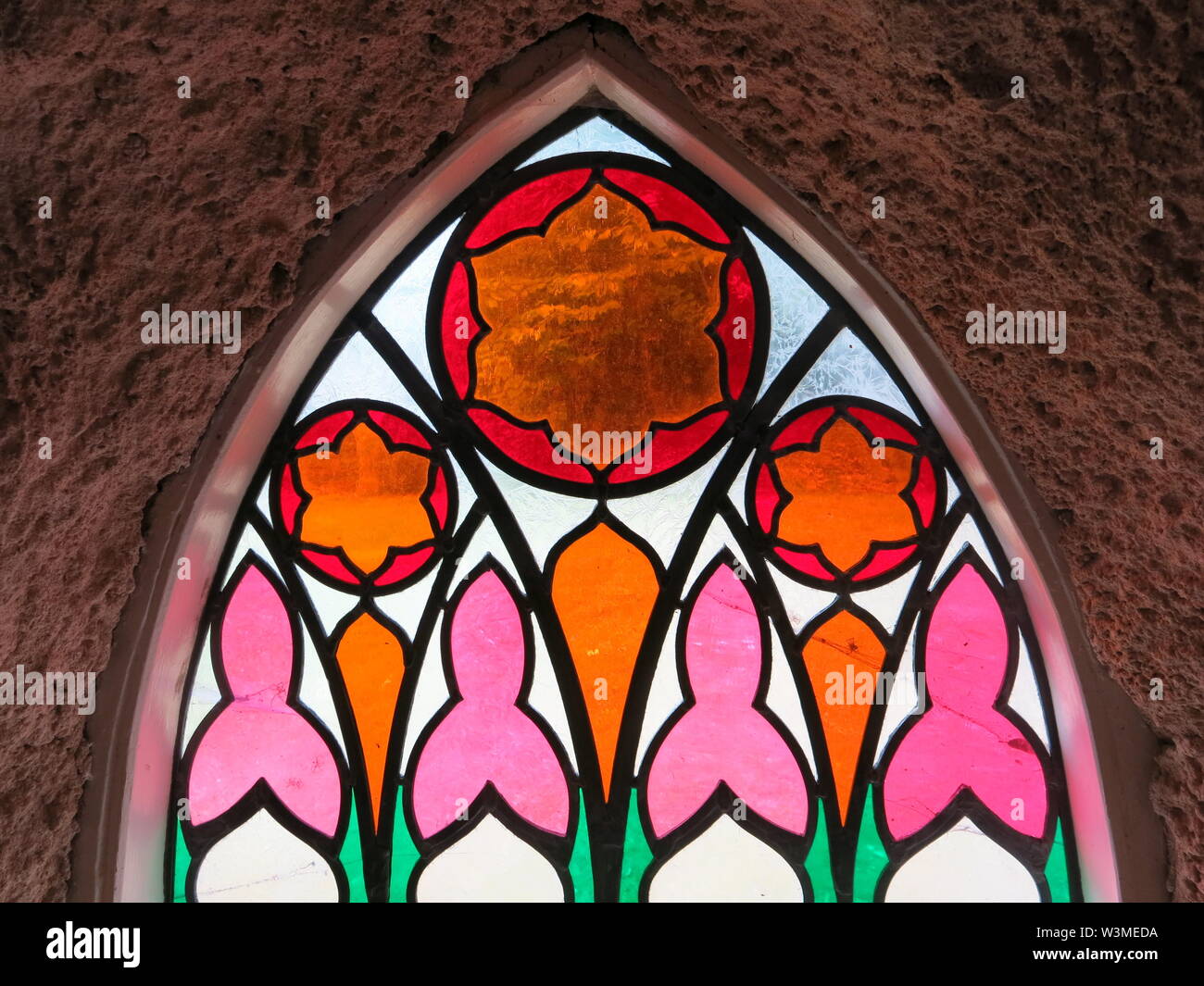 Close-up of part of an arched, floral, stained glass window in one of ...