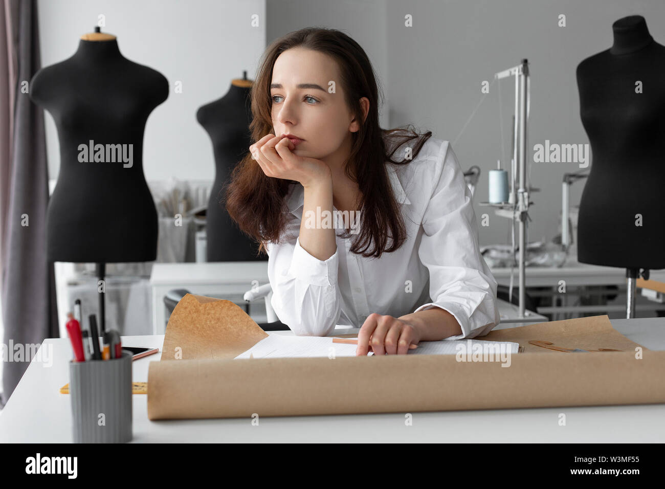 Fashion designer thinking at desk Stock Photo - Alamy