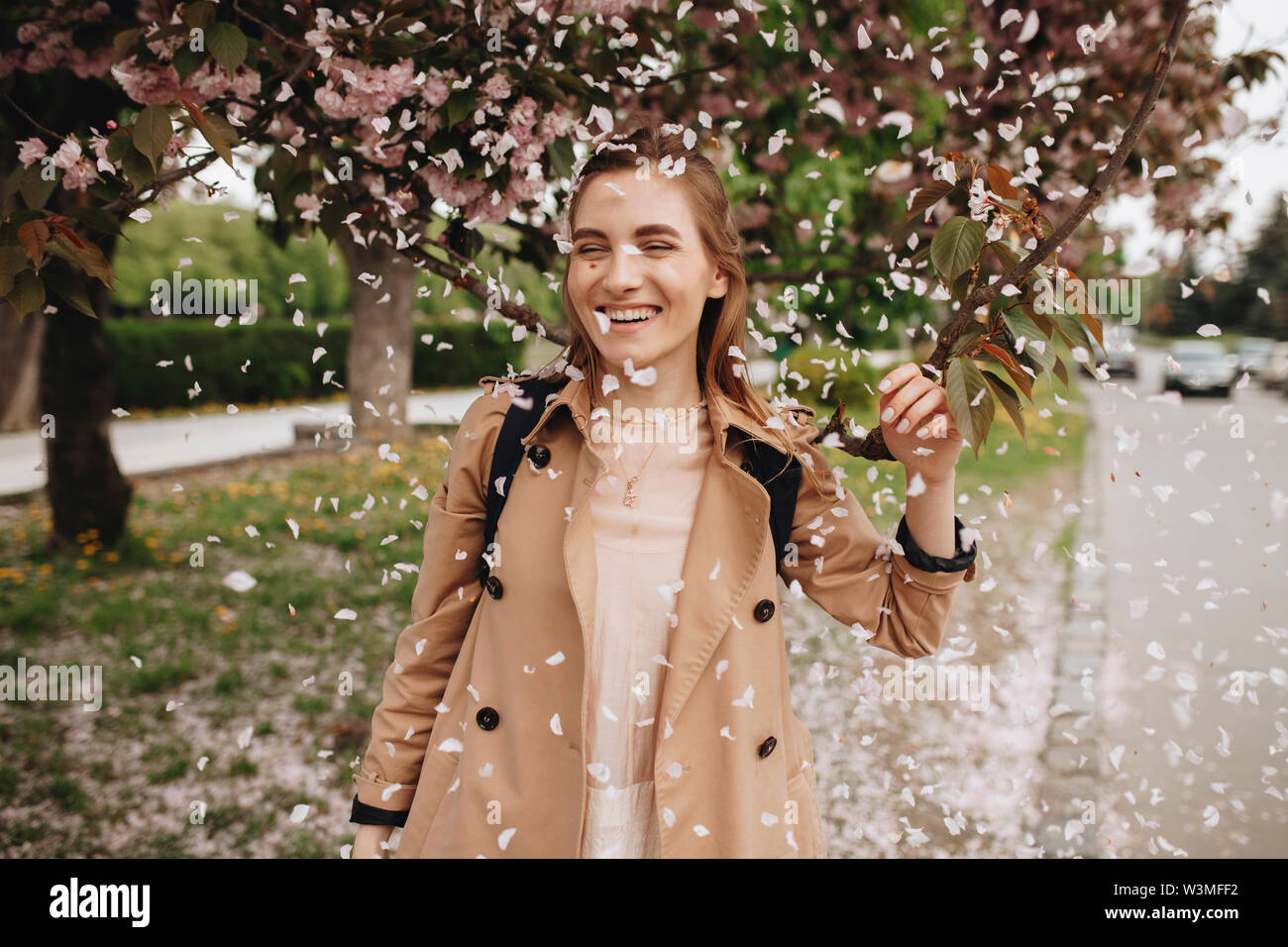 Smiling woman among falling petals from tree in bloom Stock Photo - Alamy