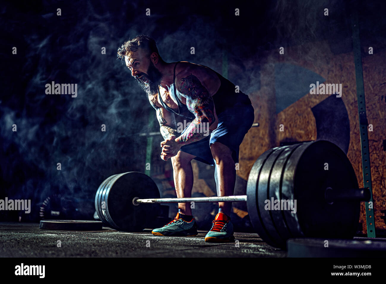 Muscular fitness man preparing to deadlift a barbell in modern fitness ...