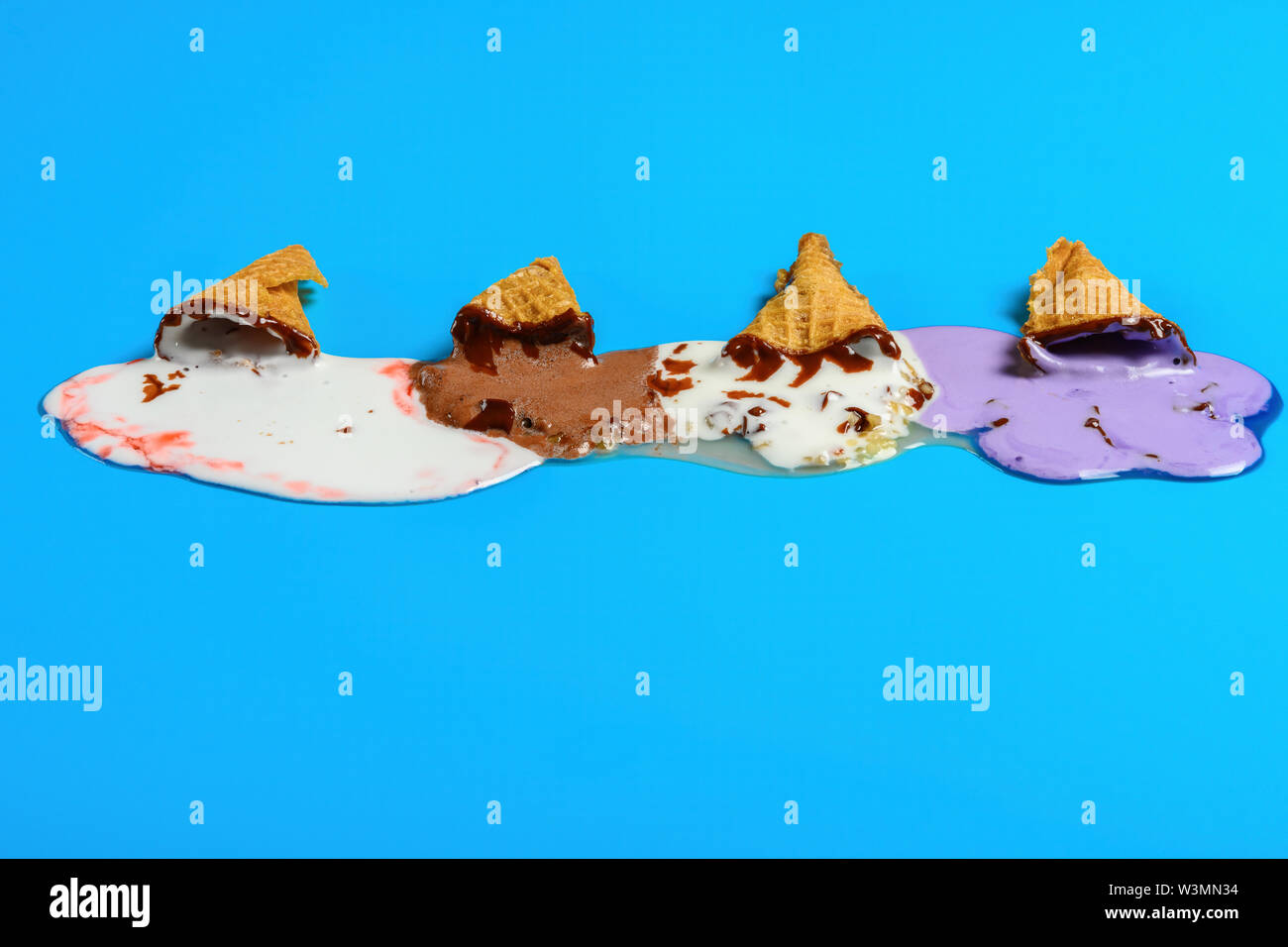 front view multiple flavor ice cream cones melted on blue background ...