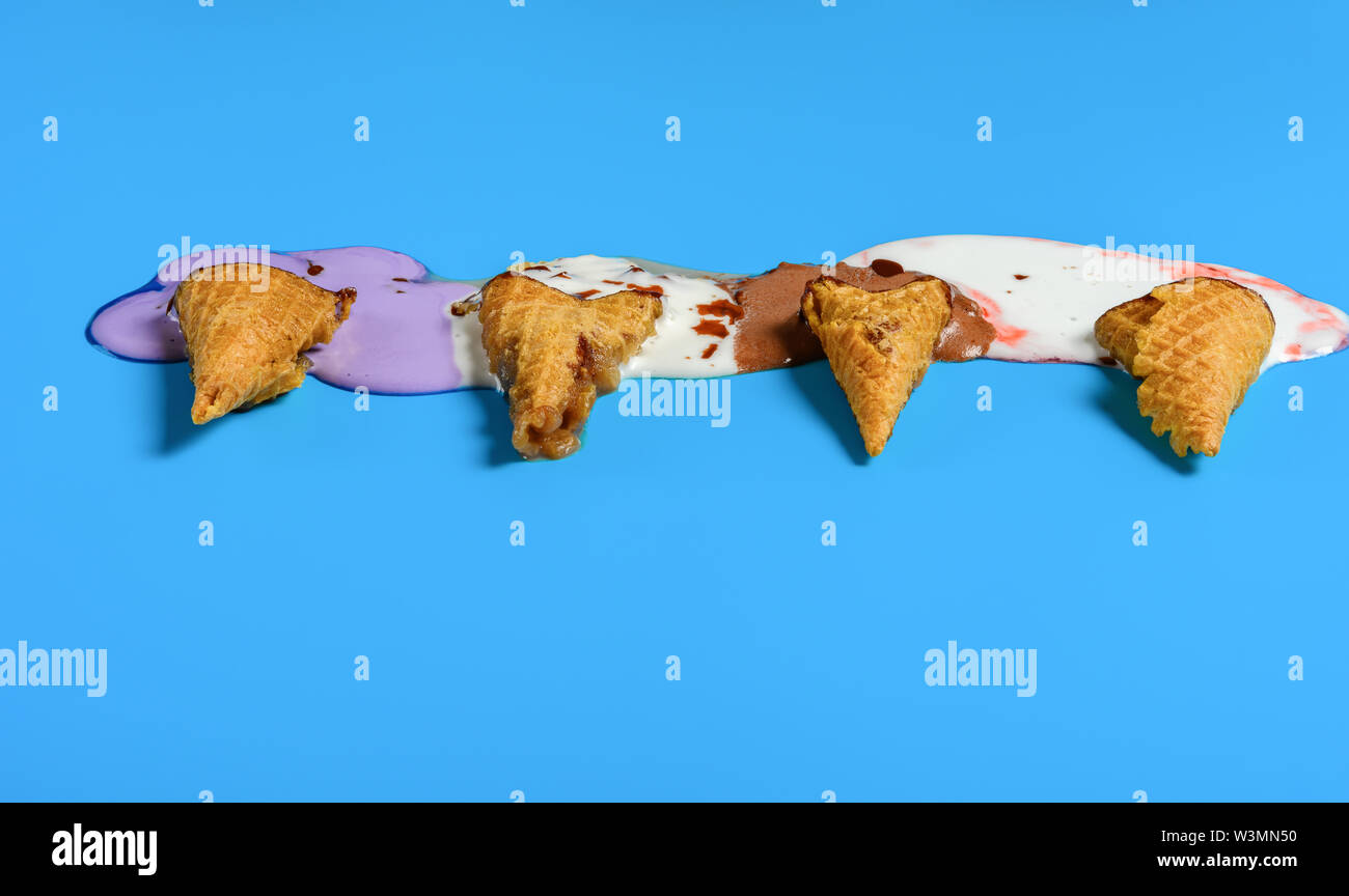 rear view multiple flavor ice cream cones melted on blue background ...