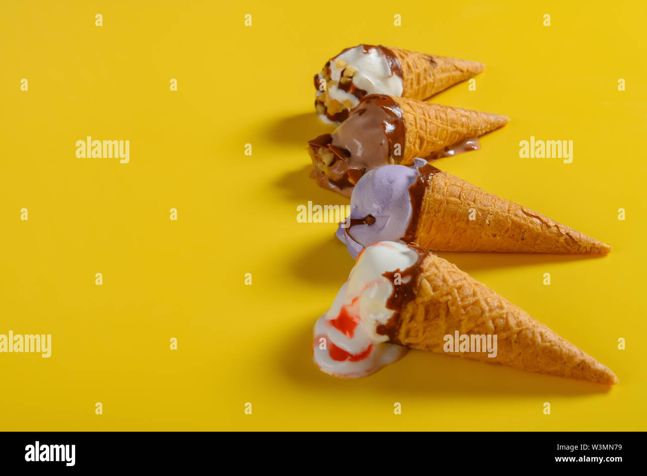 multiple flavor ice cream cones in a melting process on yellow ...