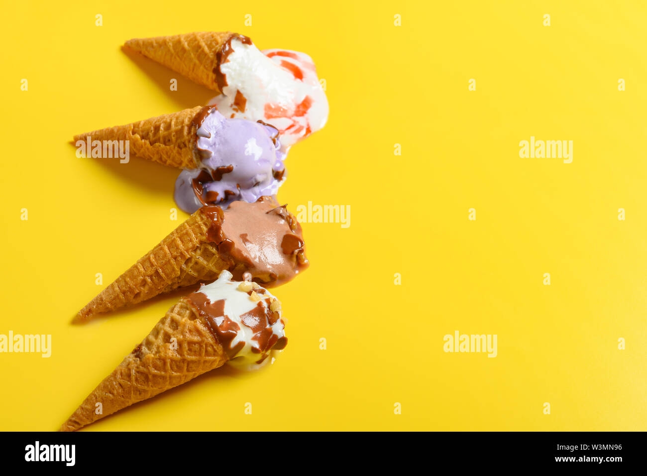 multiple flavor ice cream cones in a melting process on yellow ...