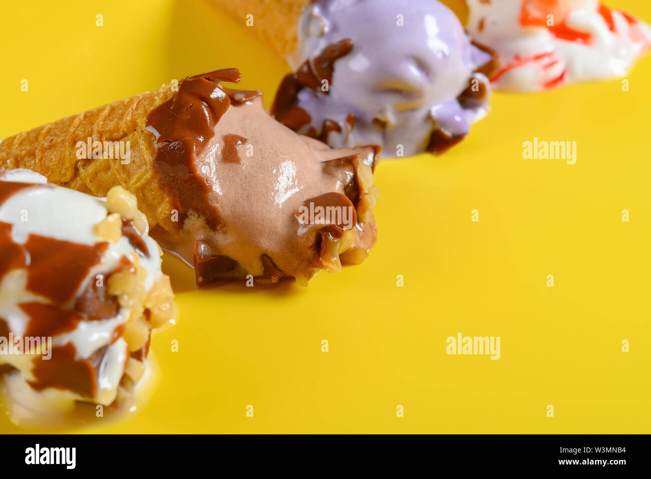 multiple flavor ice cream cones in a melting process on yellow ...