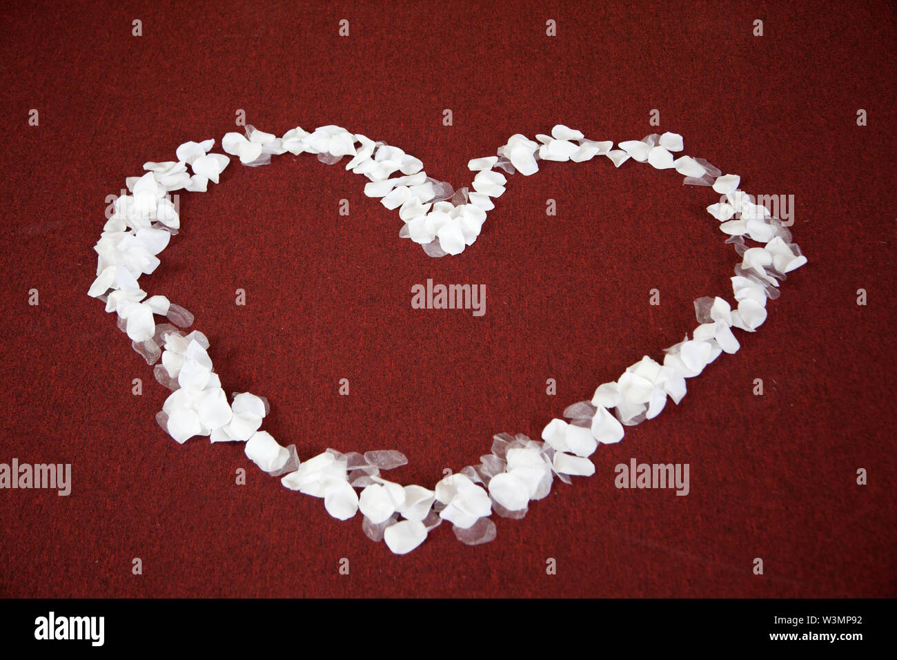 On a red carpet, white flower petals make the shape of a heart Stock ...
