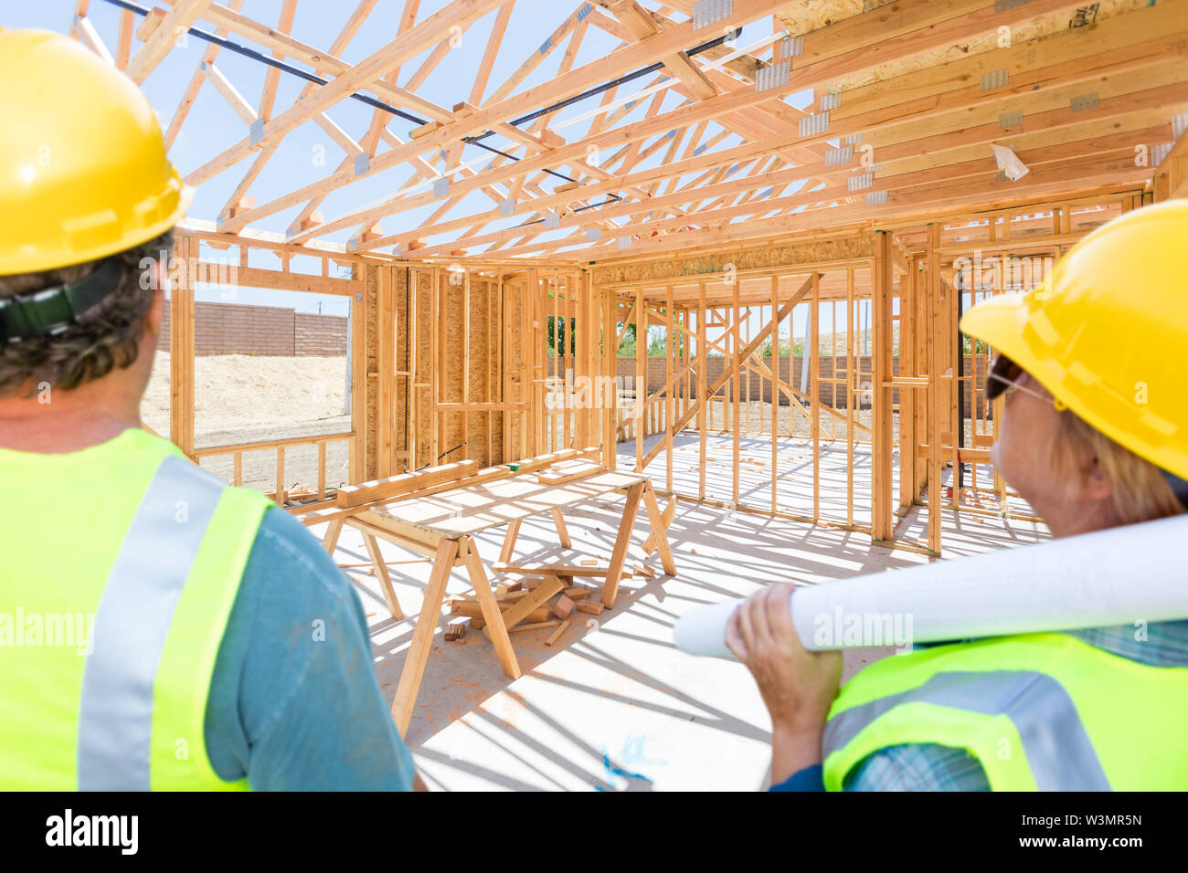 Male and Female Contractors Overlooking New House Framing At ...