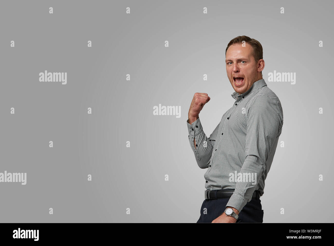 Happy excite young man in grey pullover screaming and celebrating his ...
