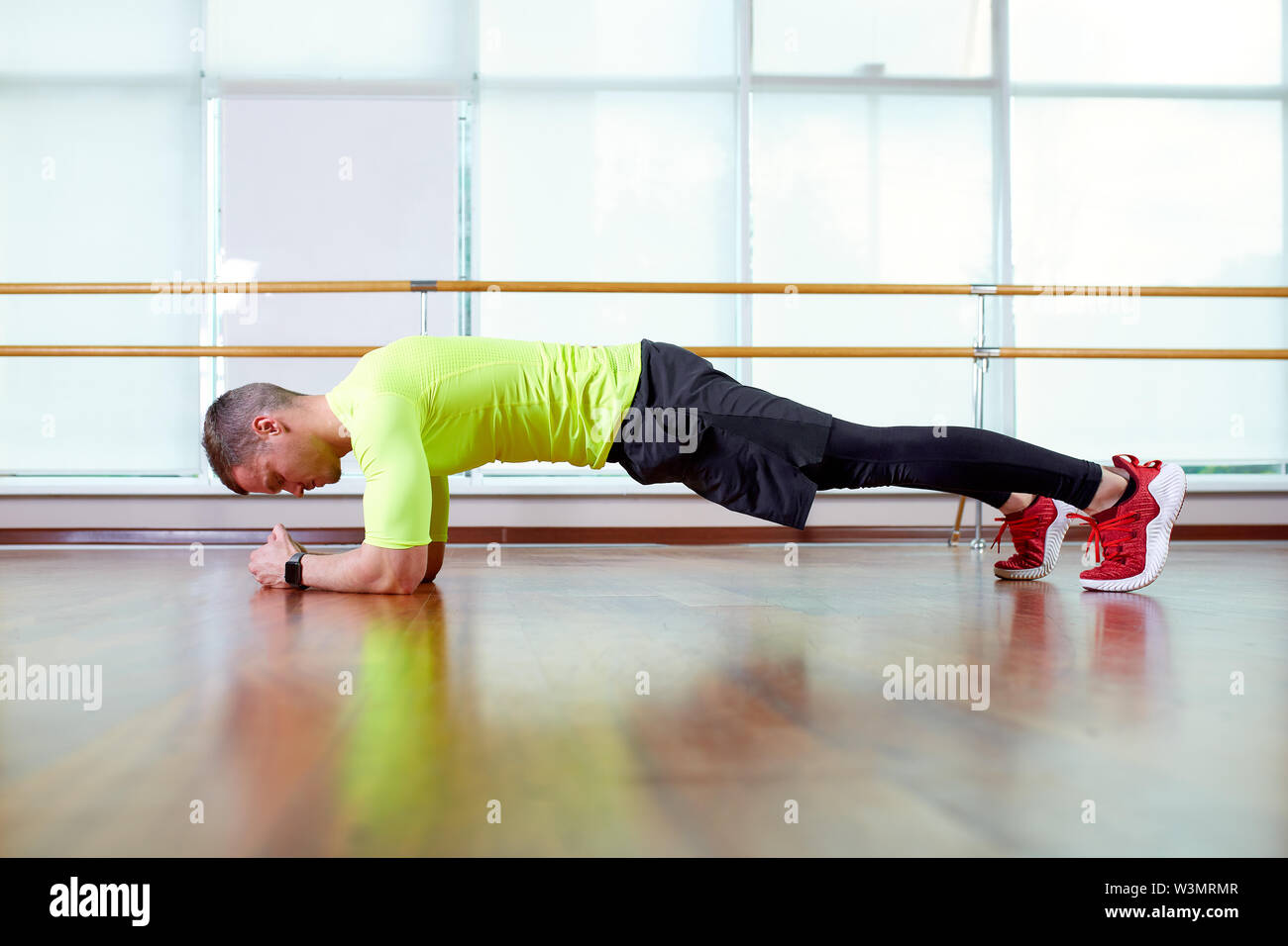 Plank it Confident muscled young man wearing sport wear and doing plank ...