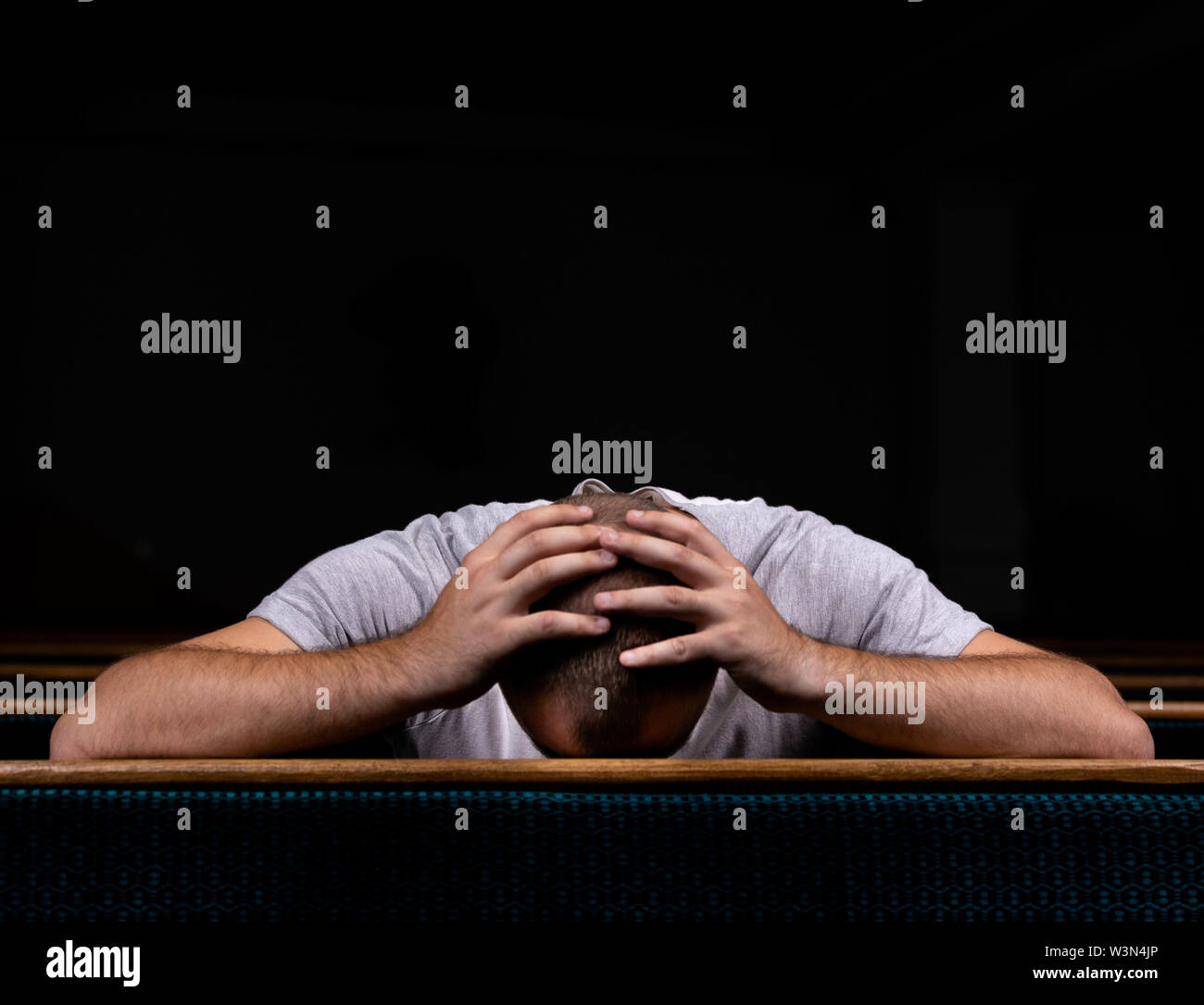 A Sad Christian man in white shirt is sitting and praying with humble ...