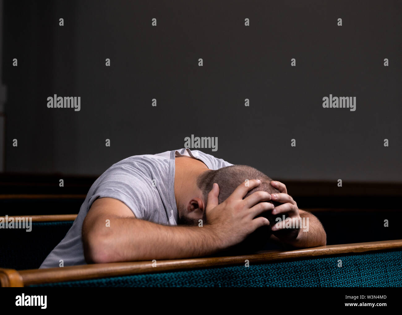 A Sad Christian man in white shirt is sitting and praying with humble ...