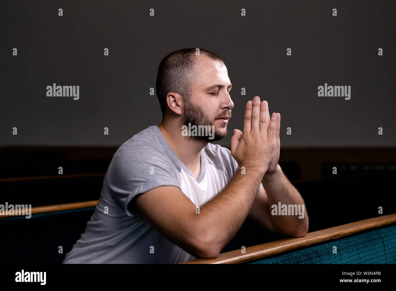 A Christian man in white shirt is sitting and praying with humble heart ...