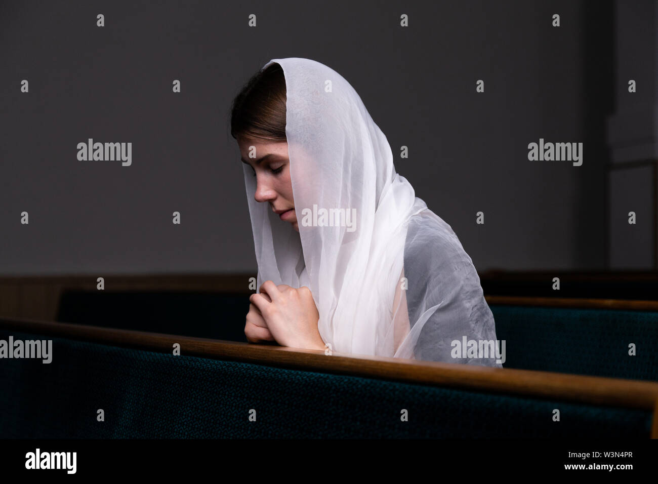 A young modest girl with a handkerchief on her head is sitting in ...
