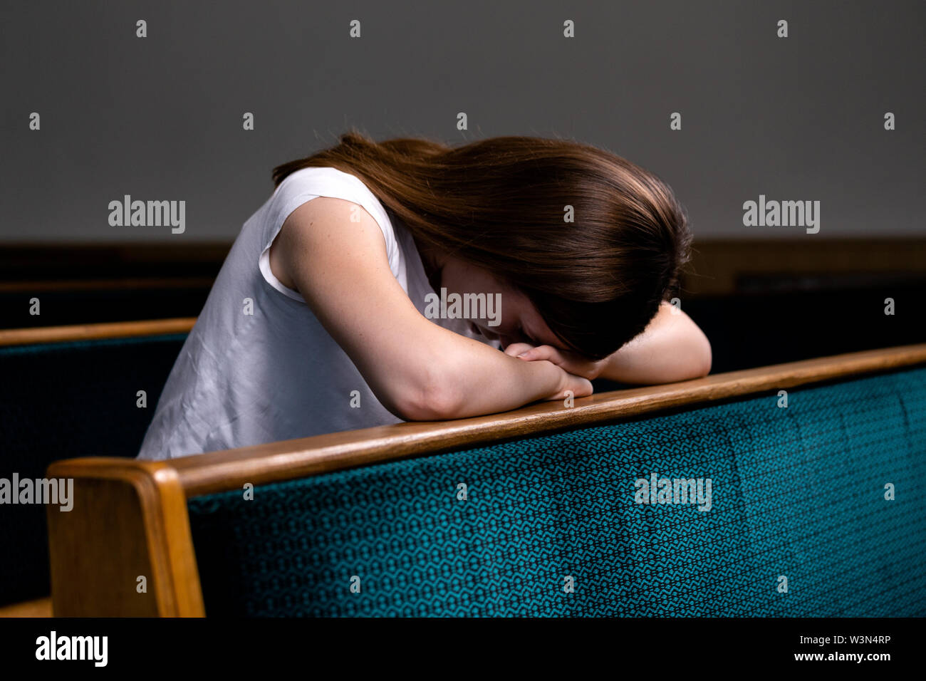 A Sad Christian girl in white shirt is sitting and praying with humble ...