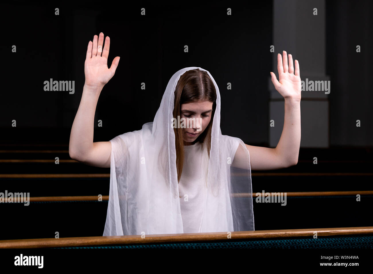 A young modest girl with a handkerchief on her head is sitting in ...