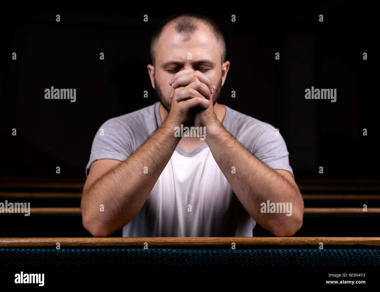 A Christian man in white shirt is sitting and praying with humble heart ...