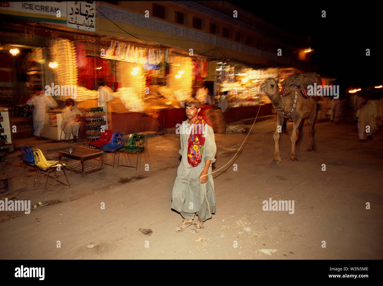 A Sindhi man walks through a bazaar with his Camel, at night, in Dadu ...