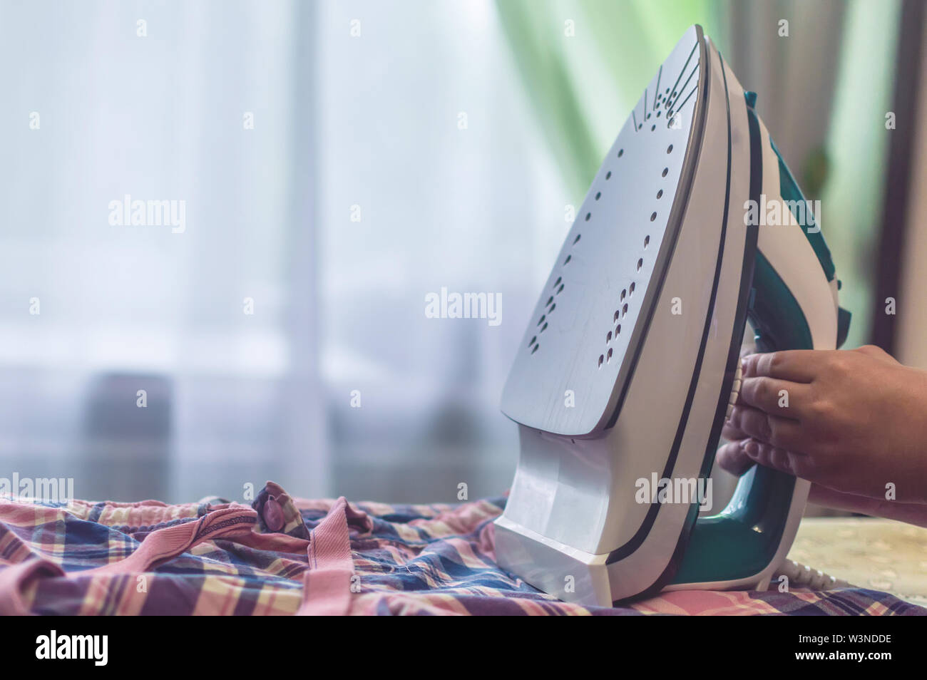 iron in the hand of the girl on the Ironing Board irons and steams ...