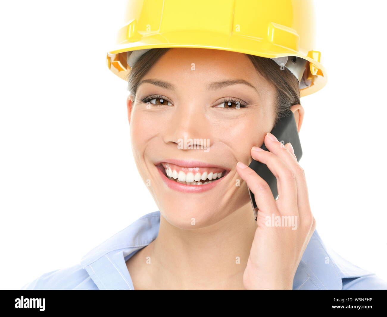 Portrait of beautiful young woman wearing hardhat using mobile phone ...